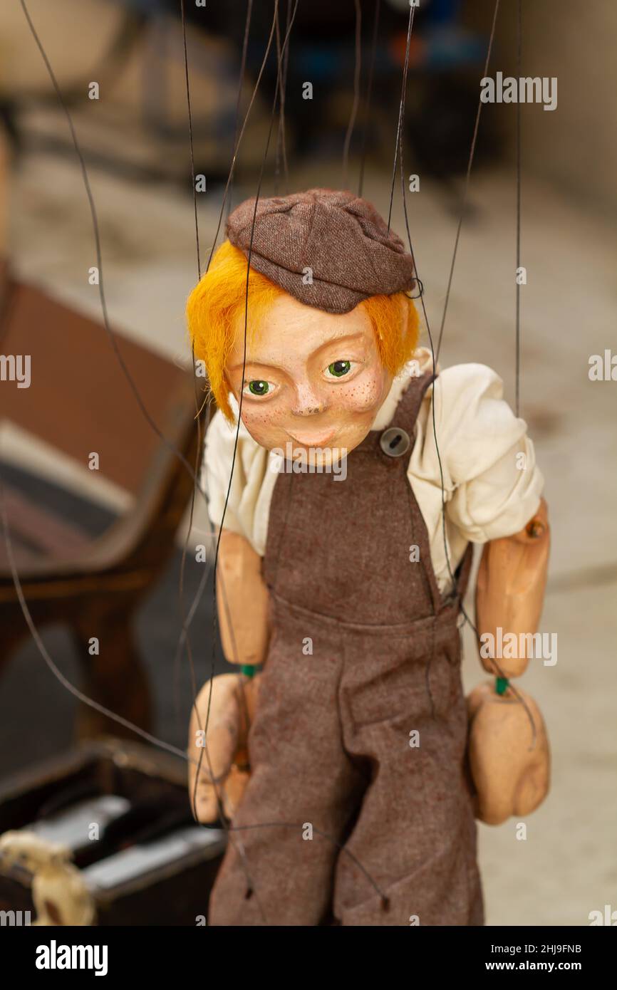 Vertical shot of a puppet with ginger hair hanging from above in string ...