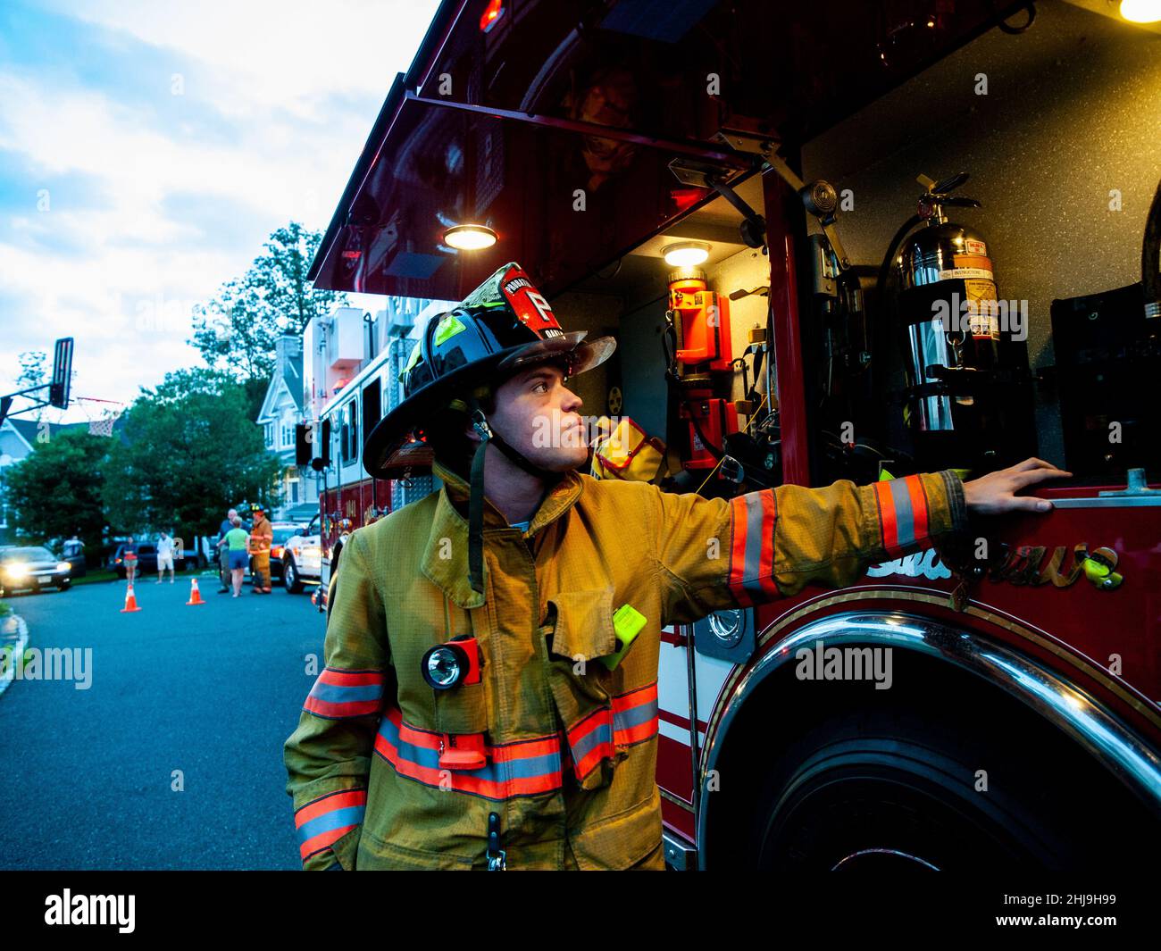 Firefighter checks truck in turnout gear Stock Photo - Alamy
