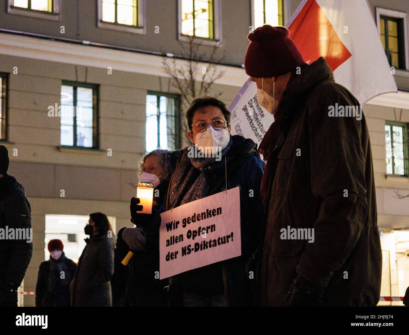 A protester holding a candle wears a sign that reads "Wir gedenken ...