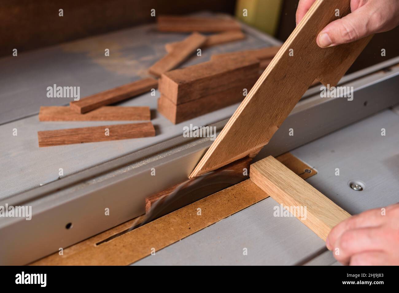 Carpenter sawing wood detail on circular saw hepling with stick for ...