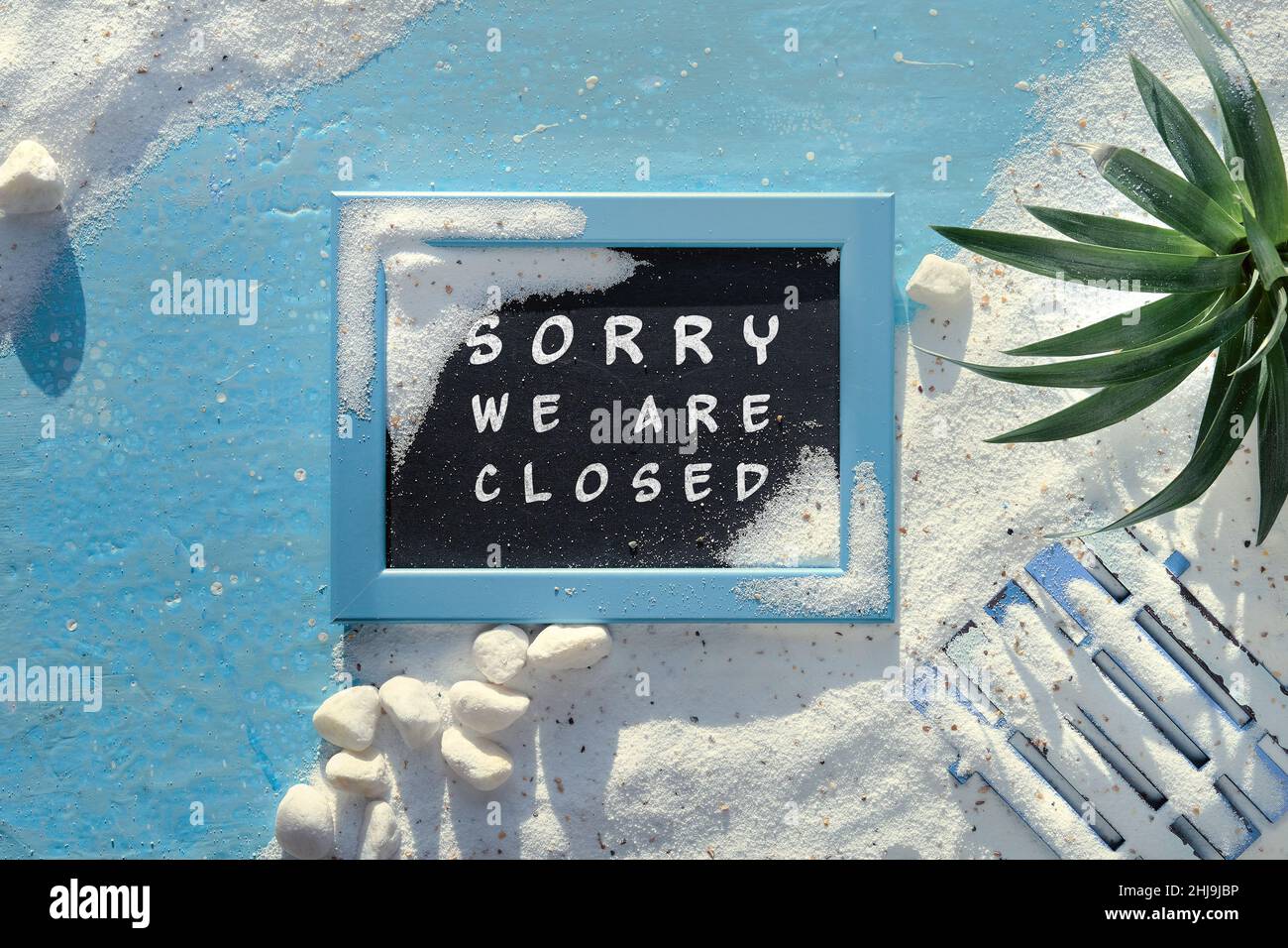 Sorry we are closed sign on blackboard. Sand background with pebbles ...