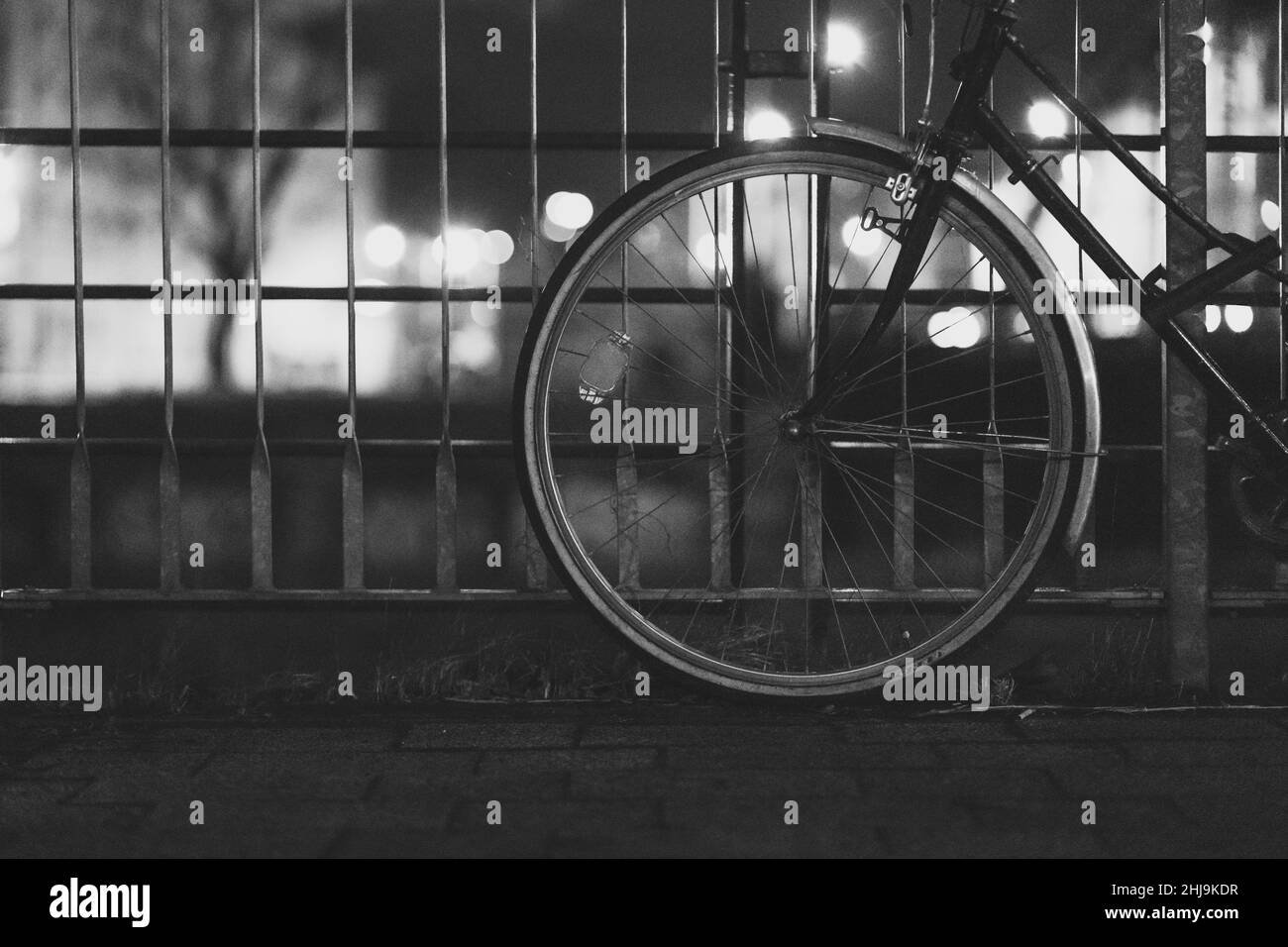 Side view of bike's front wheel attached to metal fence Stock Photo - Alamy