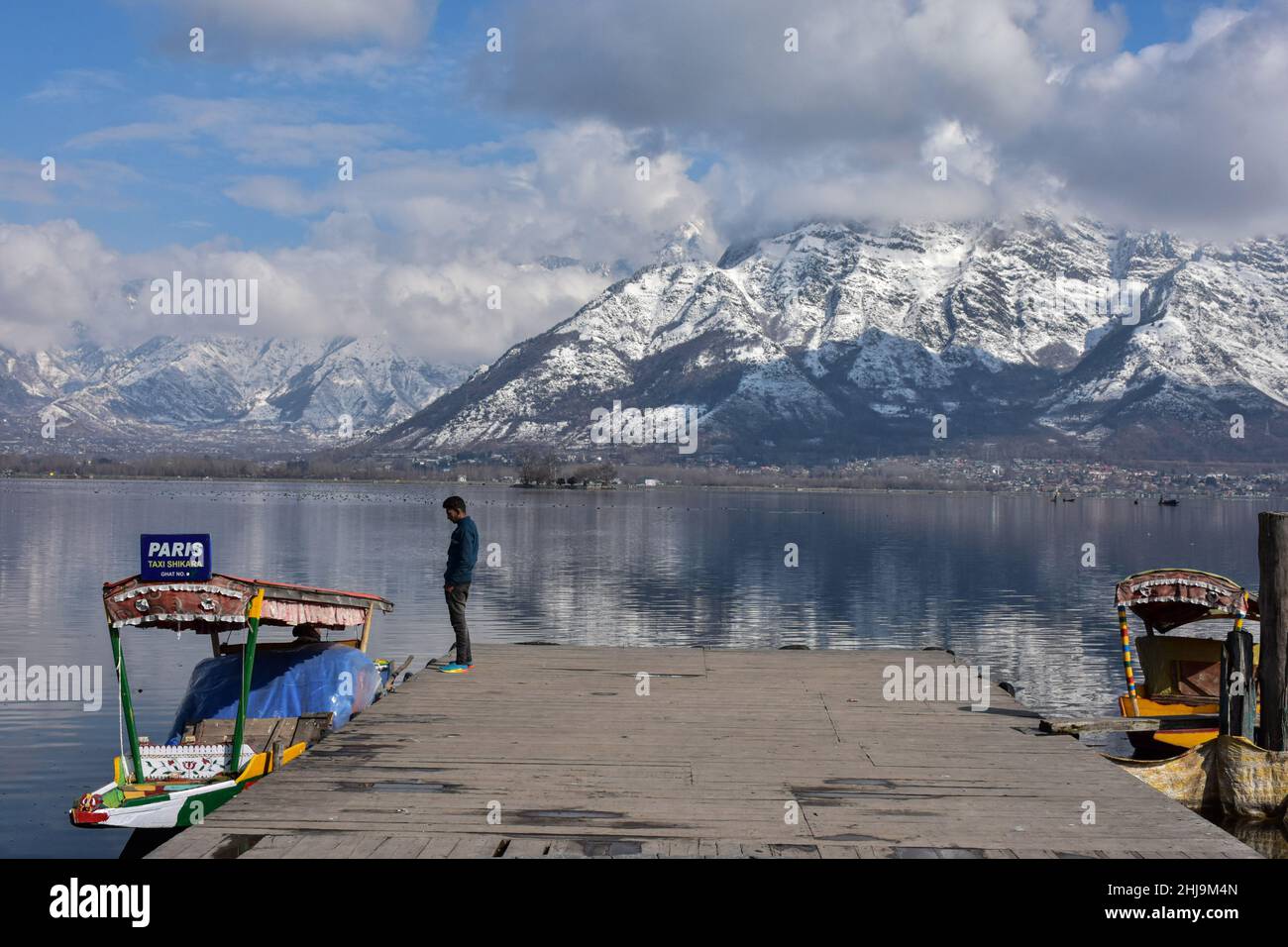 A man seen standing on a bank of Dal lake during a sunny winter day in ...