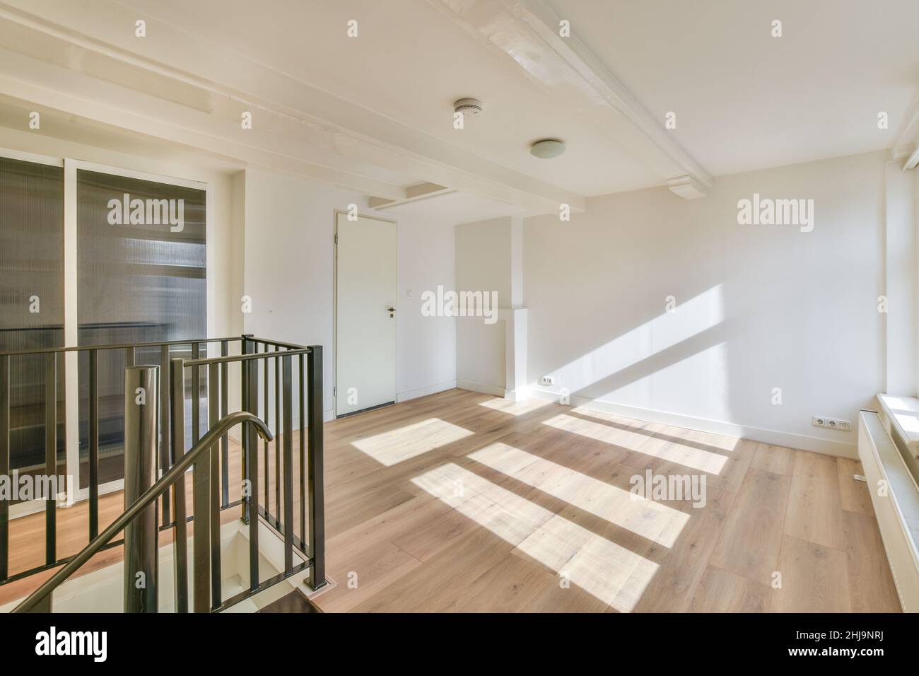 bright empty hall with large windows and stairs access to the down ...