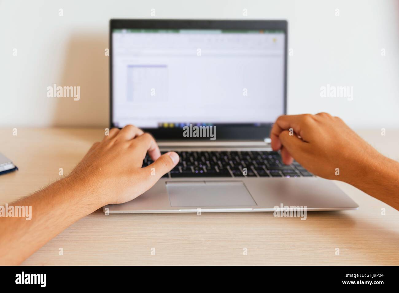 Front view of a home workspace with computer on and hands typing ...
