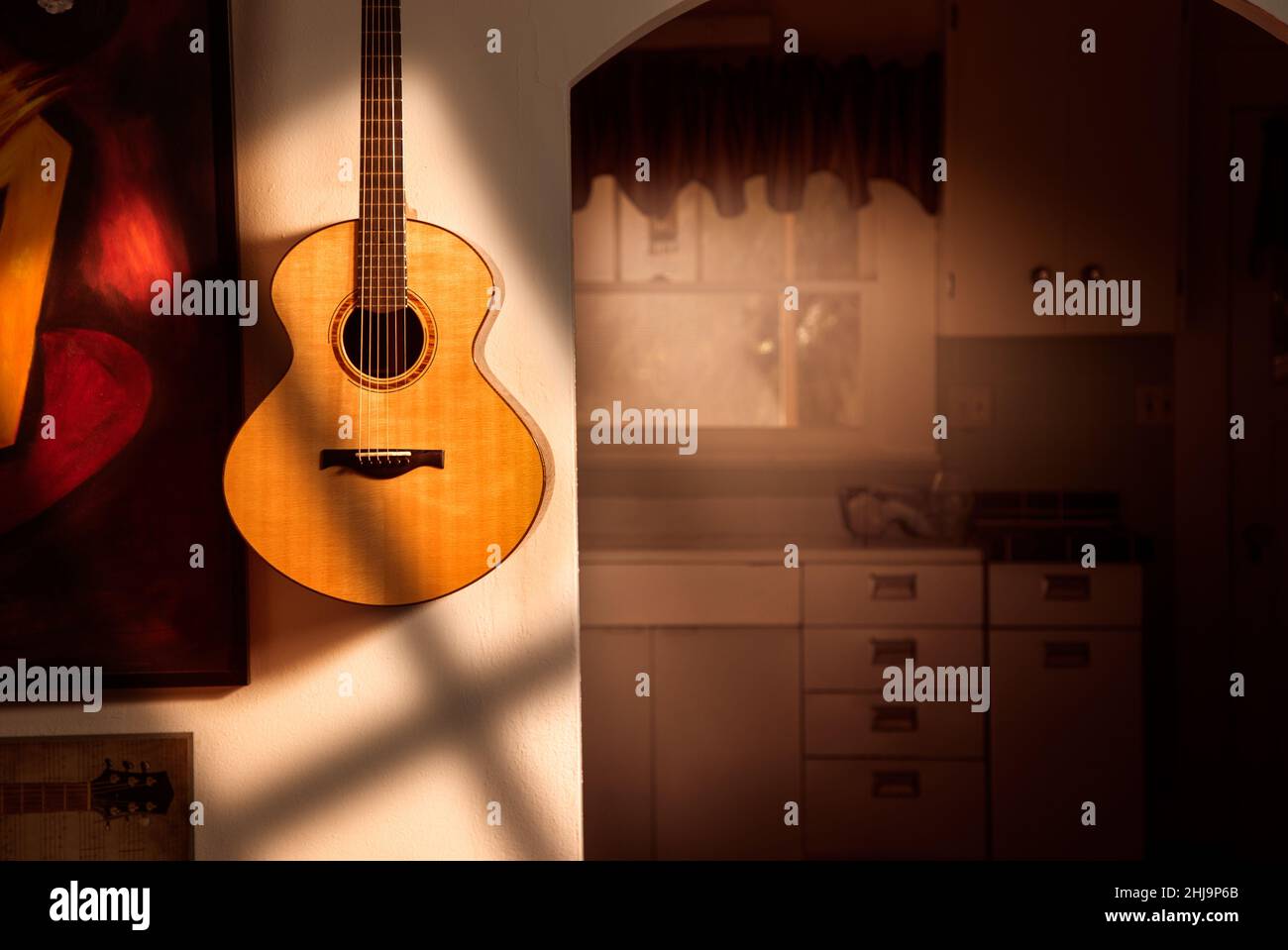 A wooden acoustic guitar placed on display inside a home and lit with a ...
