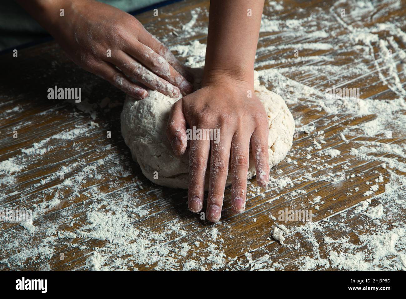 A picture of female baker chef in a kitchen kneading flour into a ...