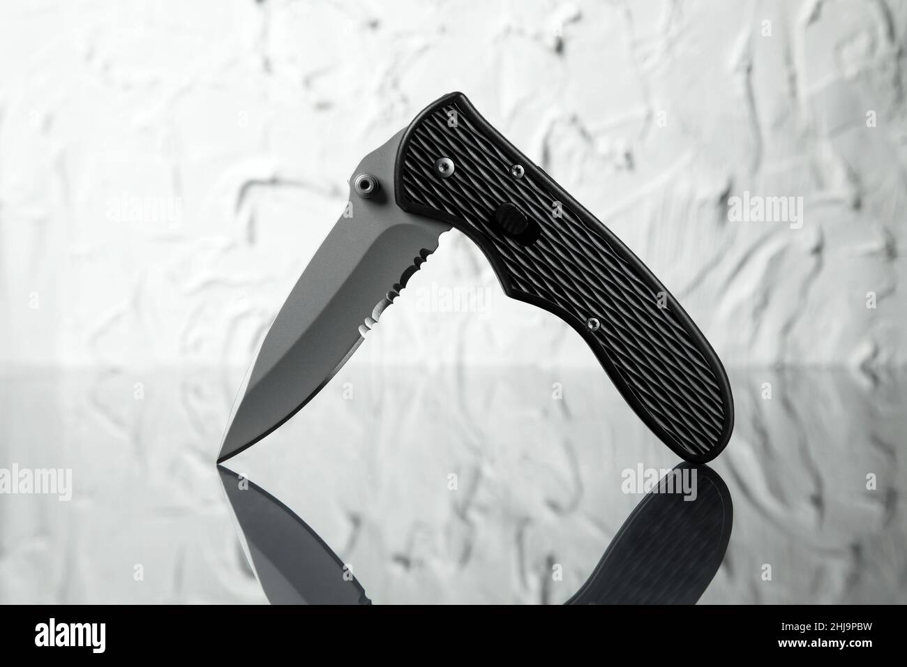 Product photography of a modern sleek black pocket knife standing half ...