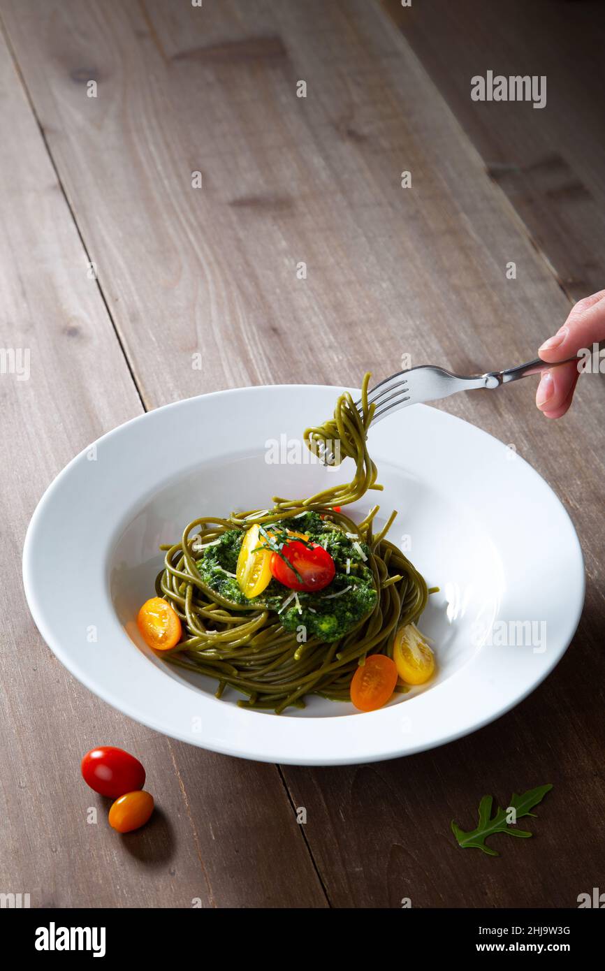 Traditional Italian green vegetarian pasta with tomatoes and pesto on a ...