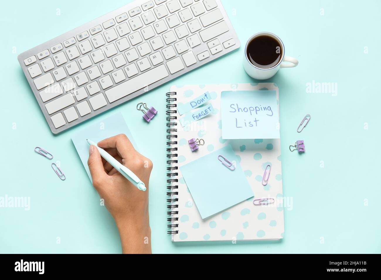 Woman with pen, stationery, computer keyboard and cup of coffee on blue ...