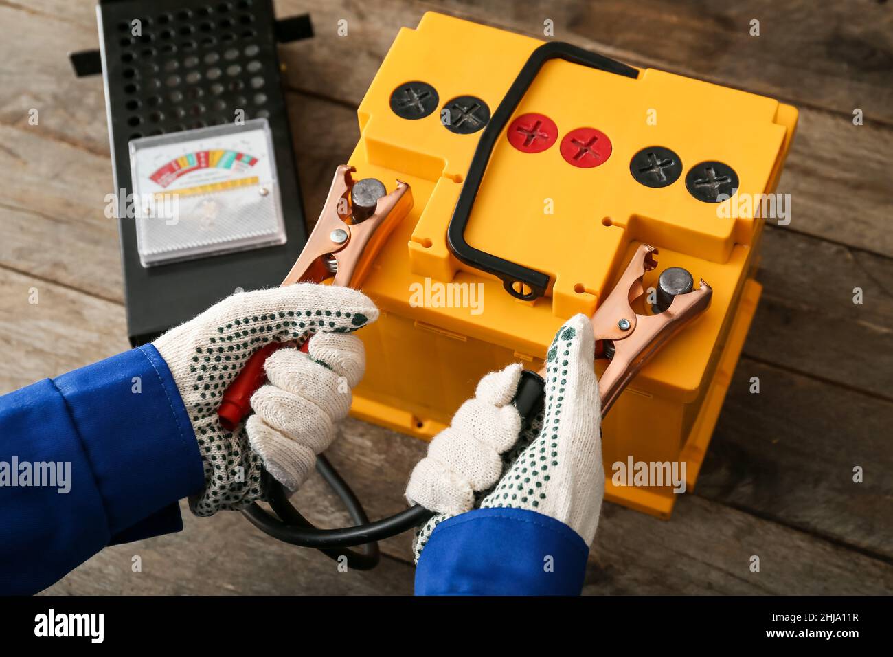 Man testing car battery on wooden background Stock Photo - Alamy
