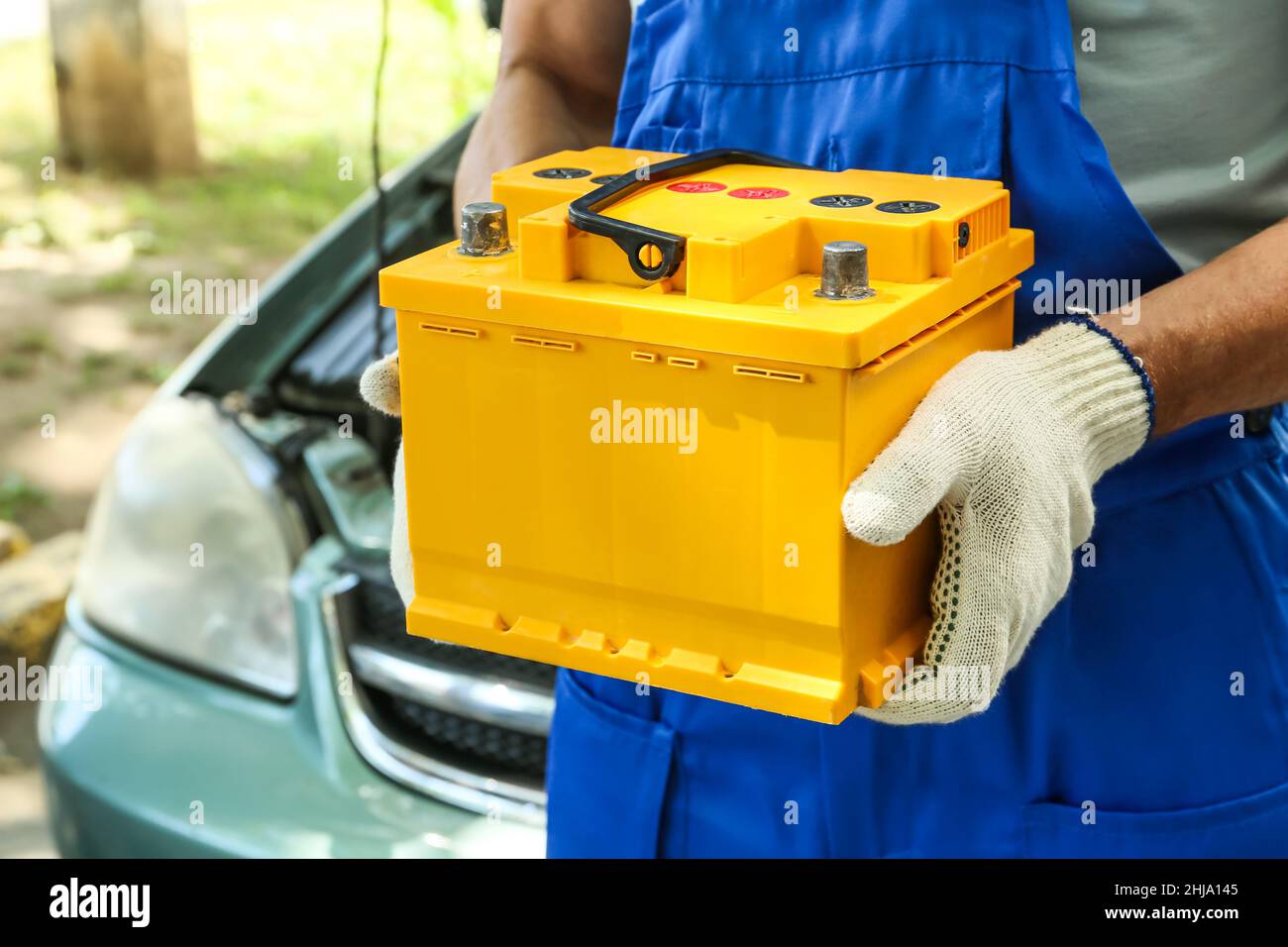 Male mechanic with modern car battery outdoors, closeup Stock Photo - Alamy