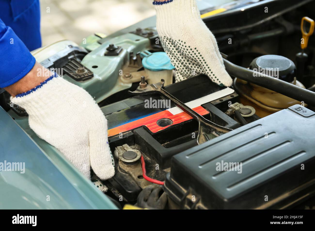 Male mechanic putting car battery in hood Stock Photo - Alamy