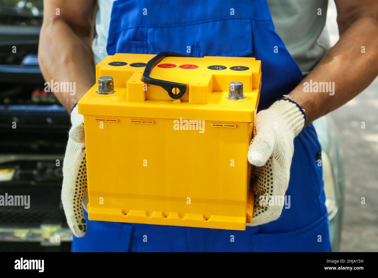 Male mechanic with modern car battery outdoors, closeup Stock Photo - Alamy
