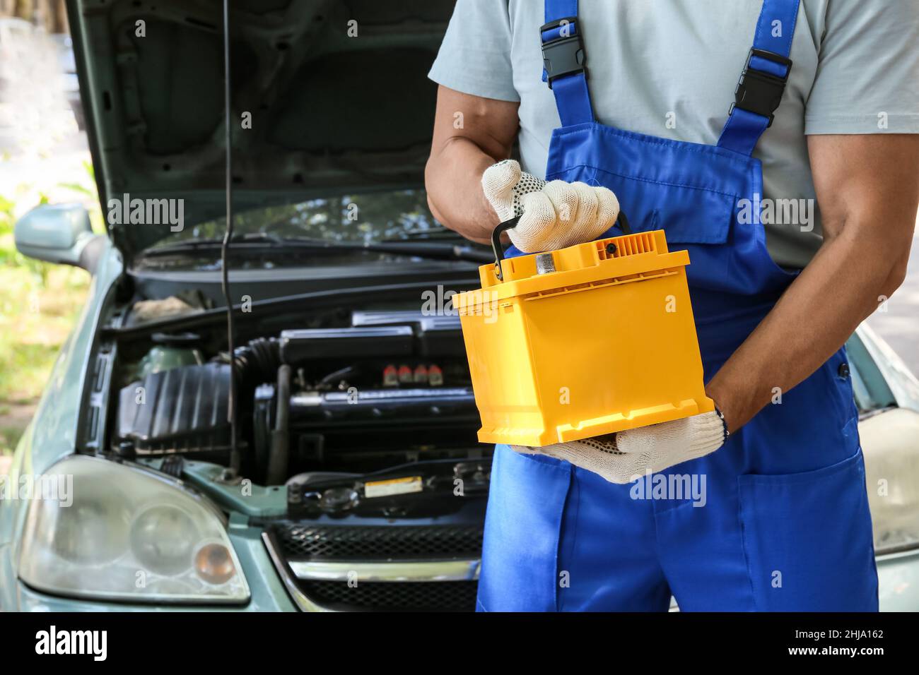 Male mechanic with modern car battery outdoors Stock Photo - Alamy