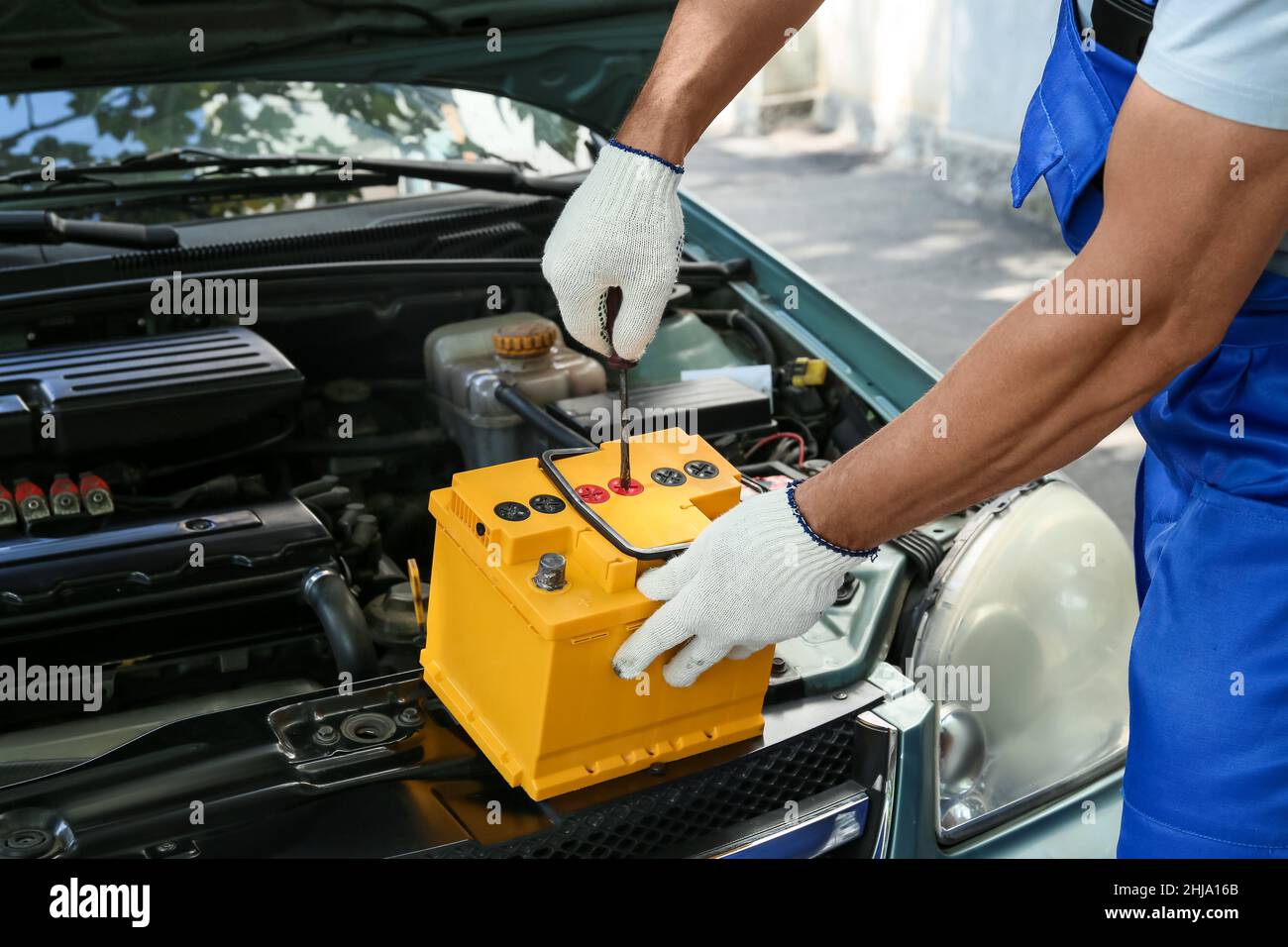 Male mechanic fixing car battery Stock Photo - Alamy