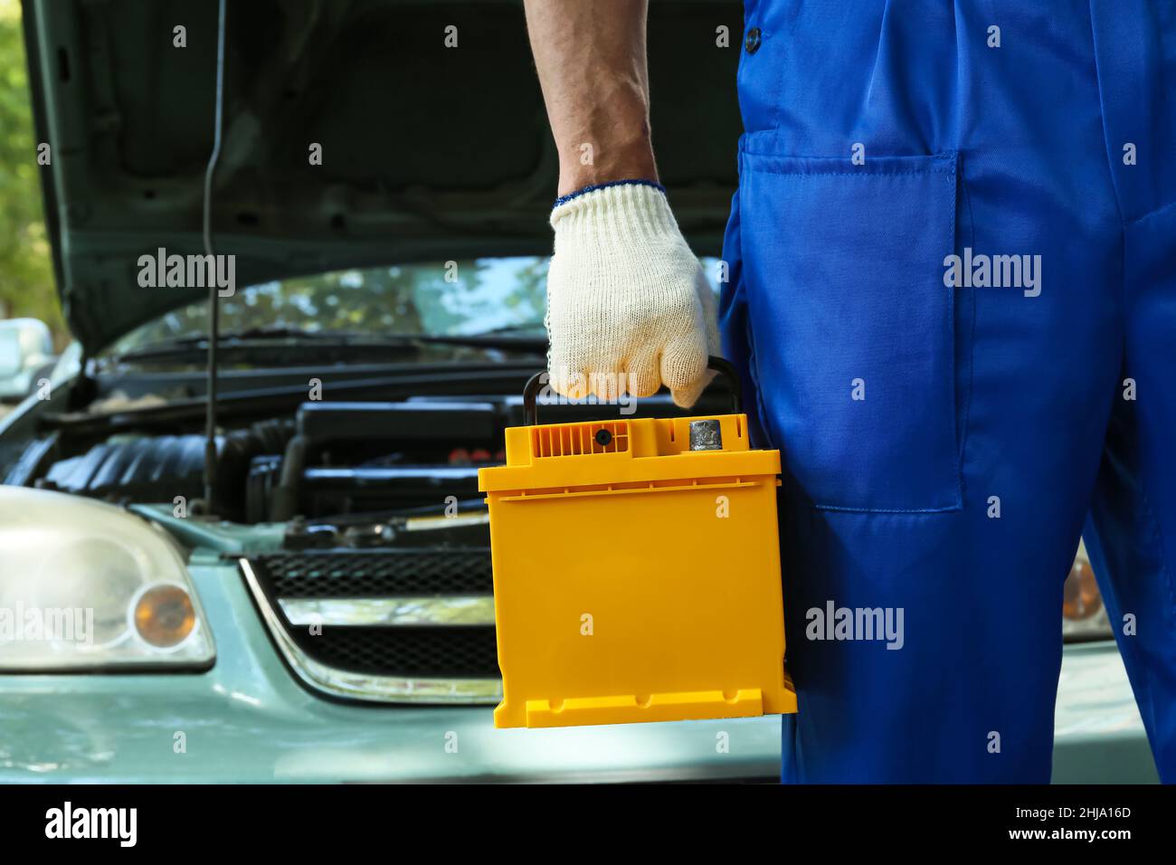 Male mechanic with modern car battery outdoors, closeup Stock Photo - Alamy
