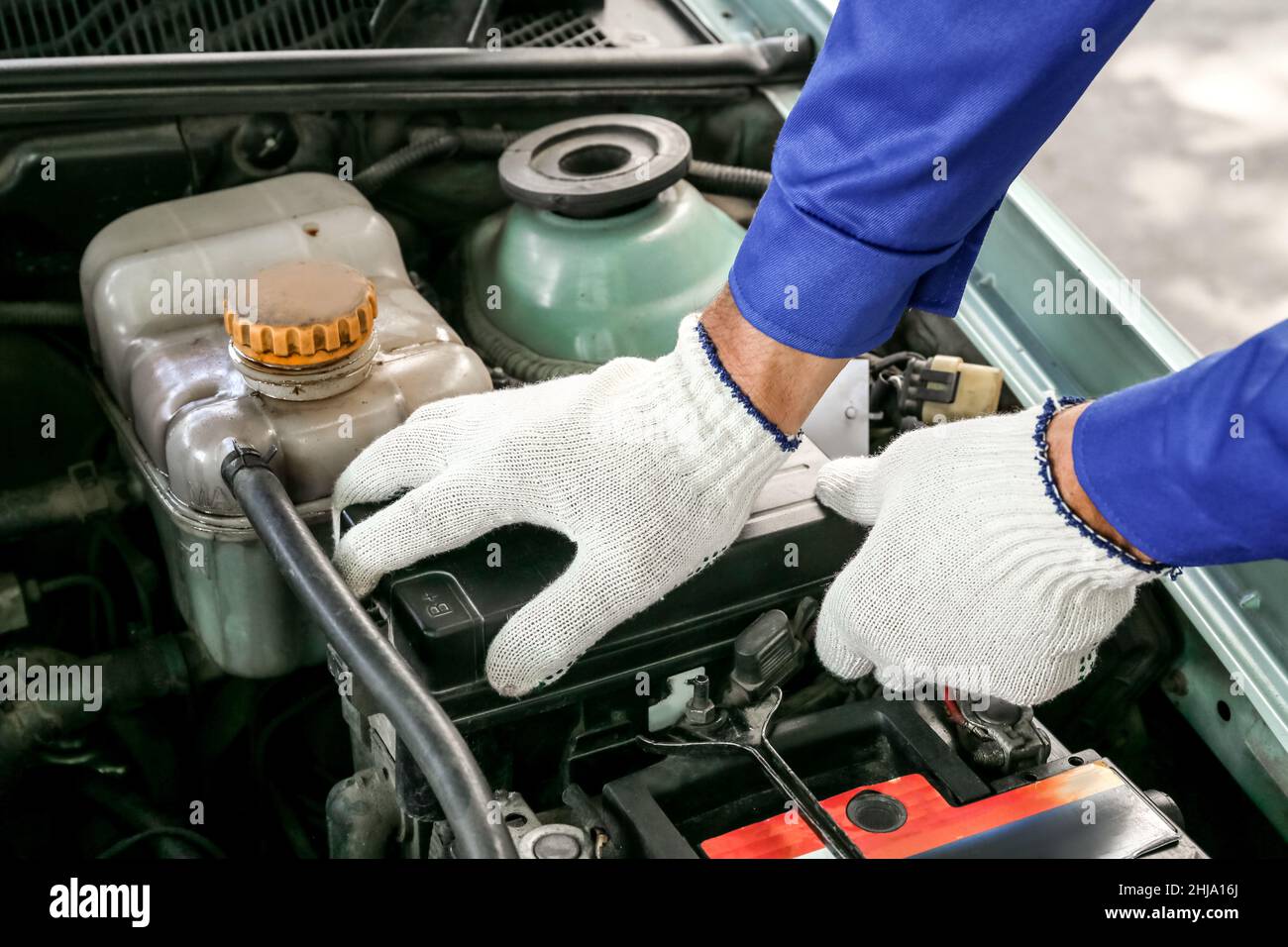 Male mechanic fixing car battery Stock Photo - Alamy