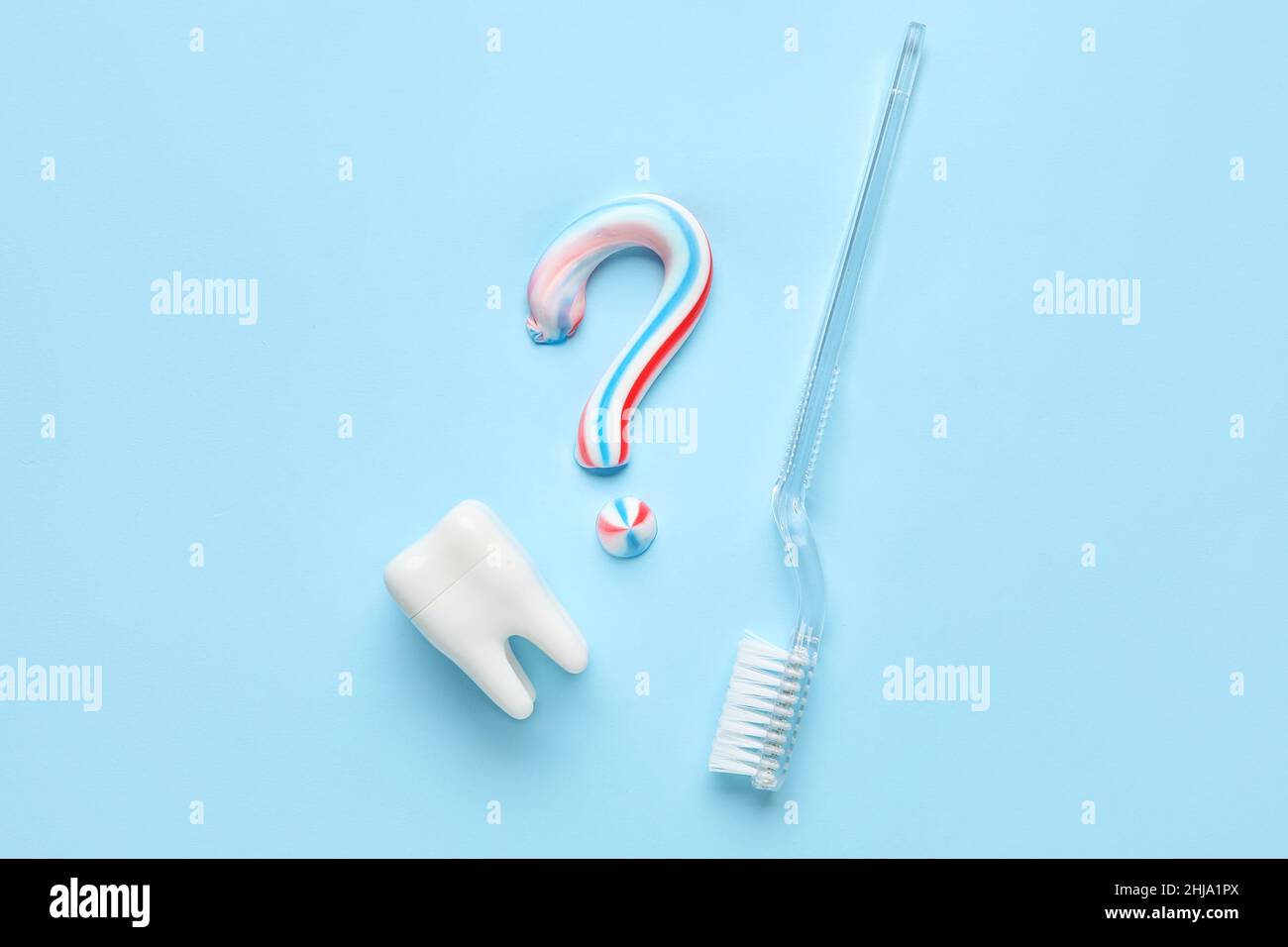 Question mark made of toothpaste, tube and brush on blue background ...
