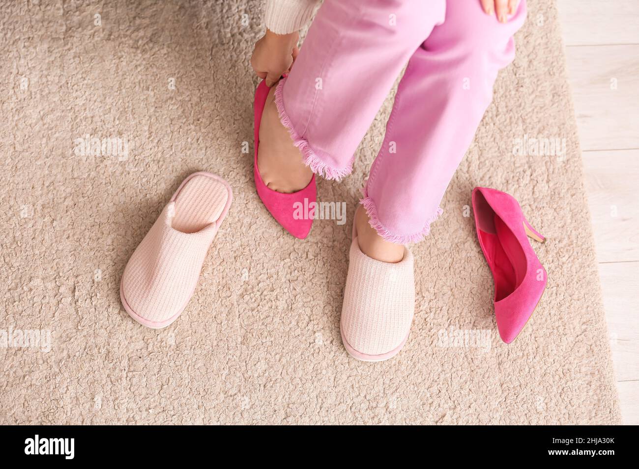 Young woman taking off high heels and putting on soft slippers at home ...