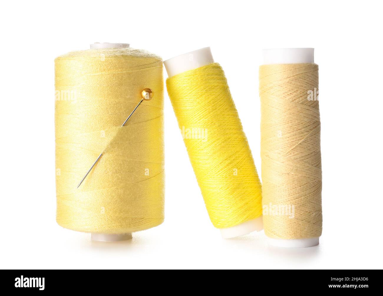 Yellow sewing thread spools with pin on white background Stock Photo ...