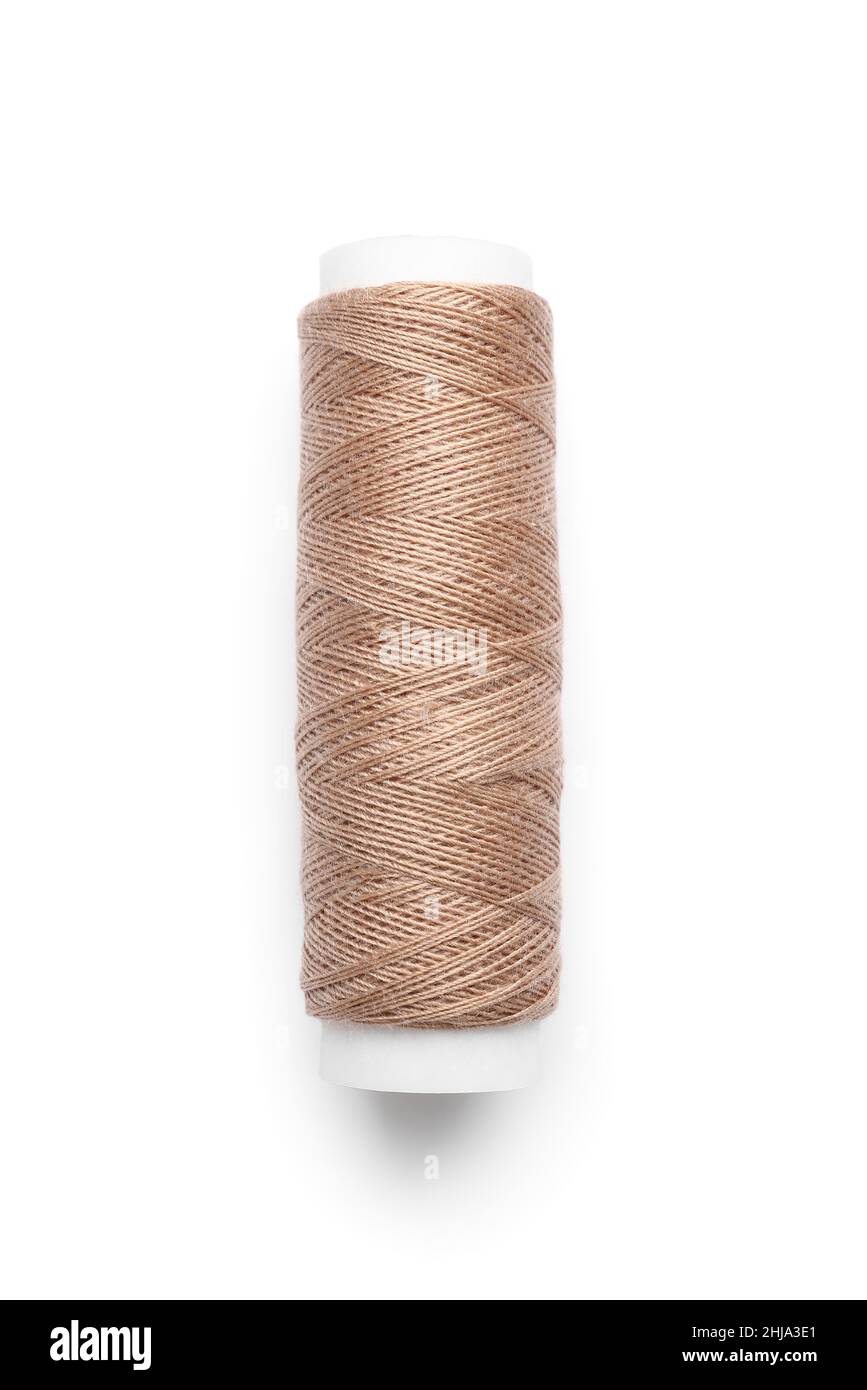 Beige sewing thread spool on white background Stock Photo - Alamy