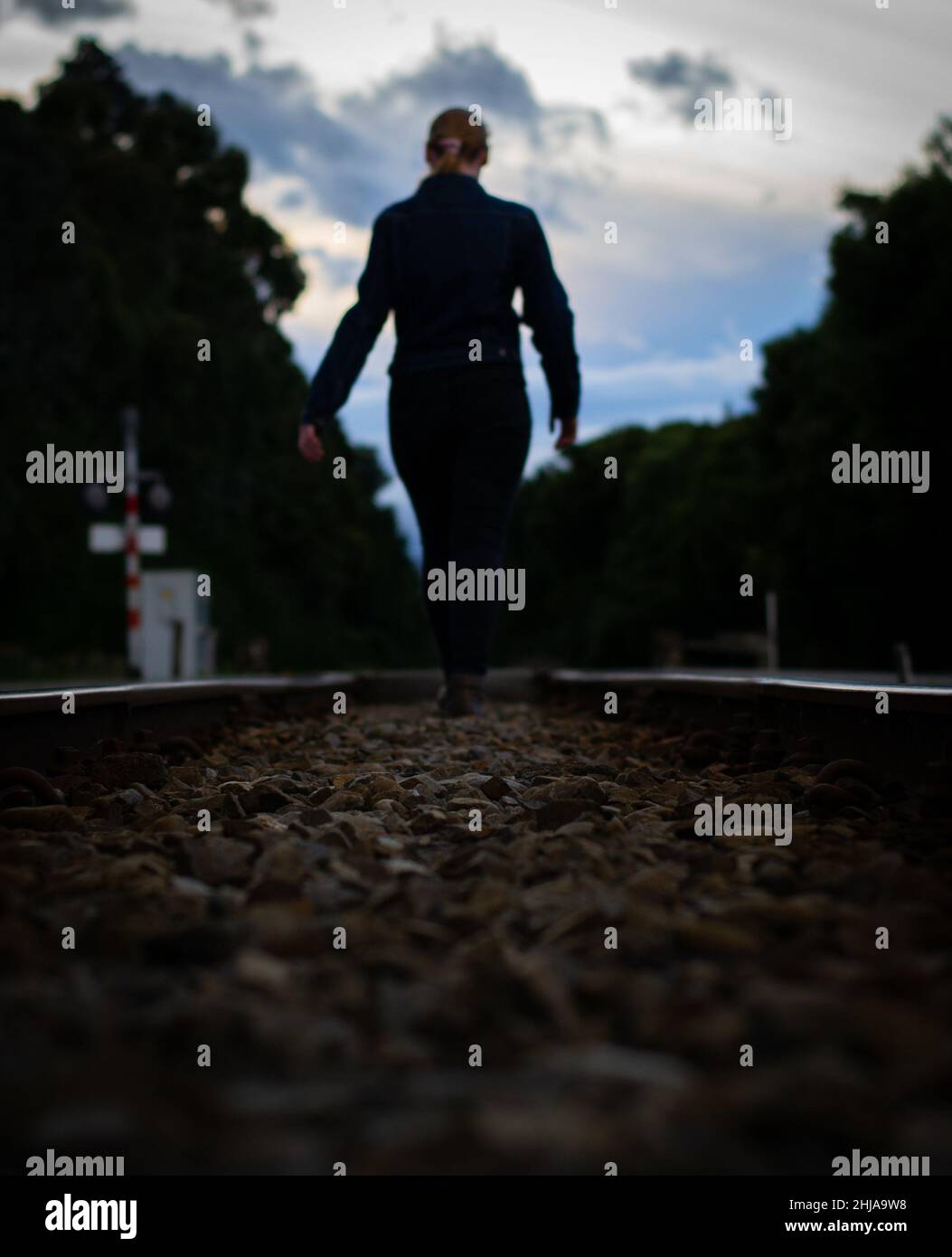Rear view of a female walking on the tracks Stock Photo - Alamy