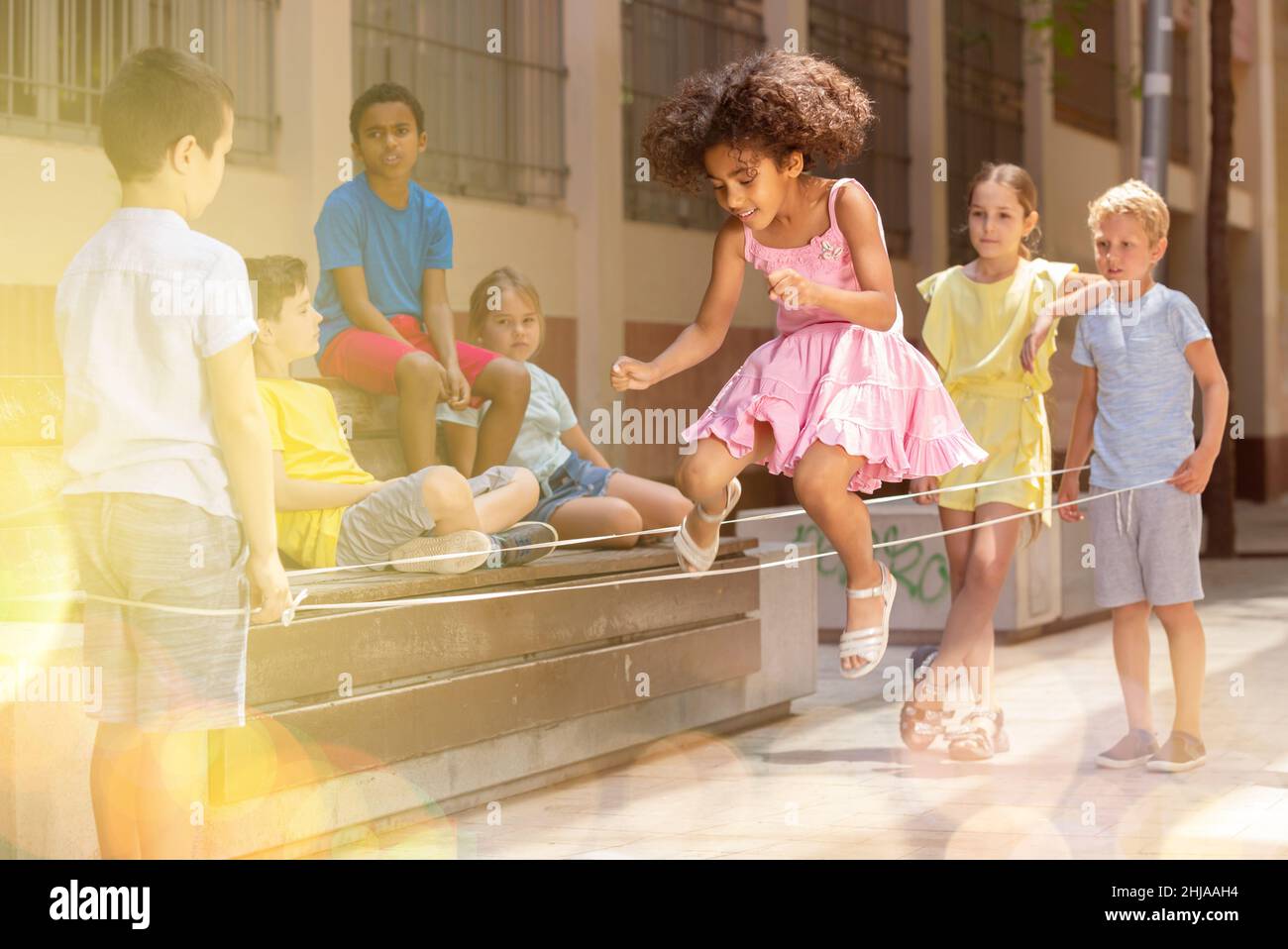 Energetic kids playing and skipping on elastic jumping rope in yard ...