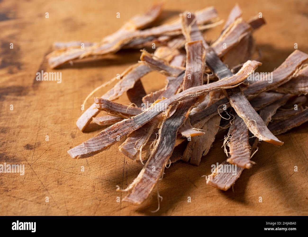 Dried squid placed on a wooden background. Surume is a Japanese snack ...