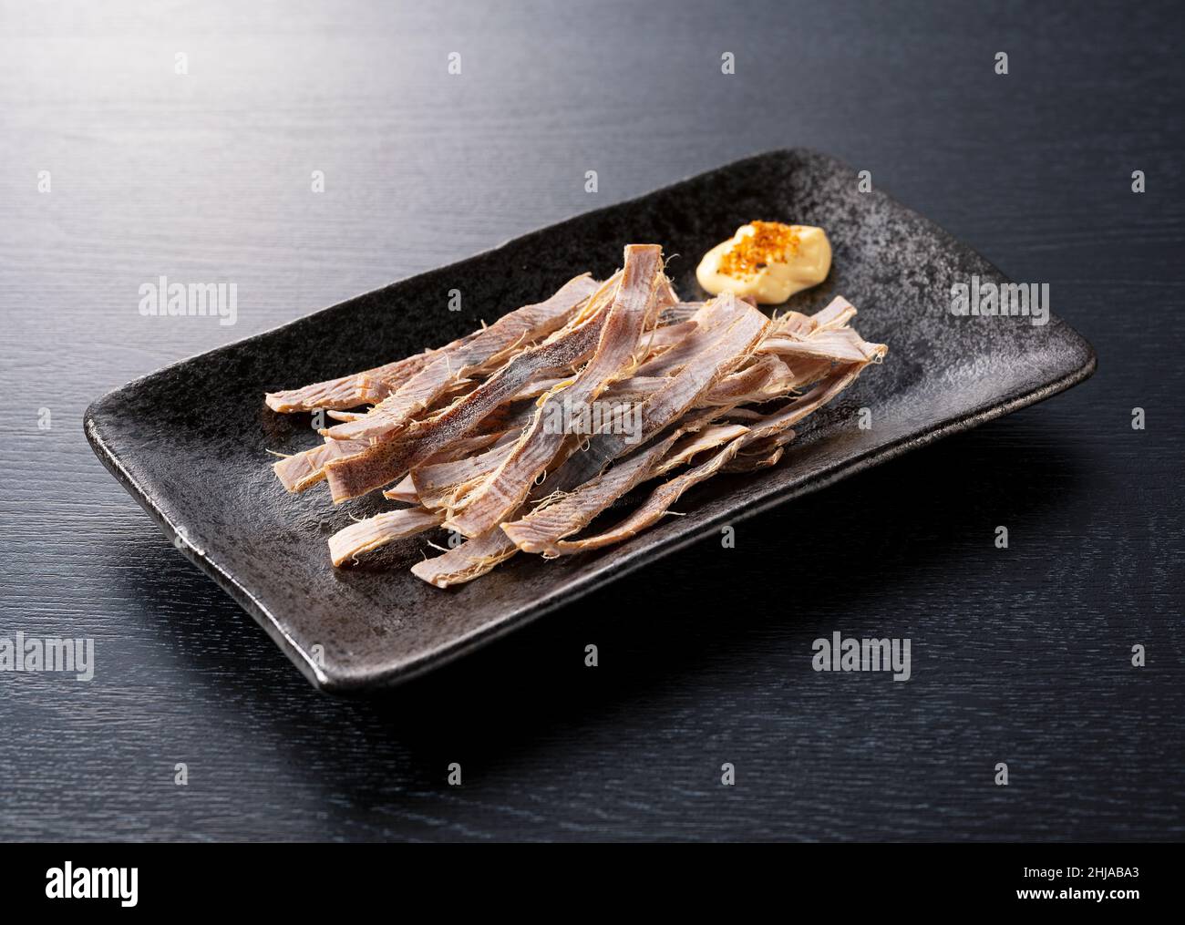 Dried squid and mayonnaise placed on a black background. Surume is a ...