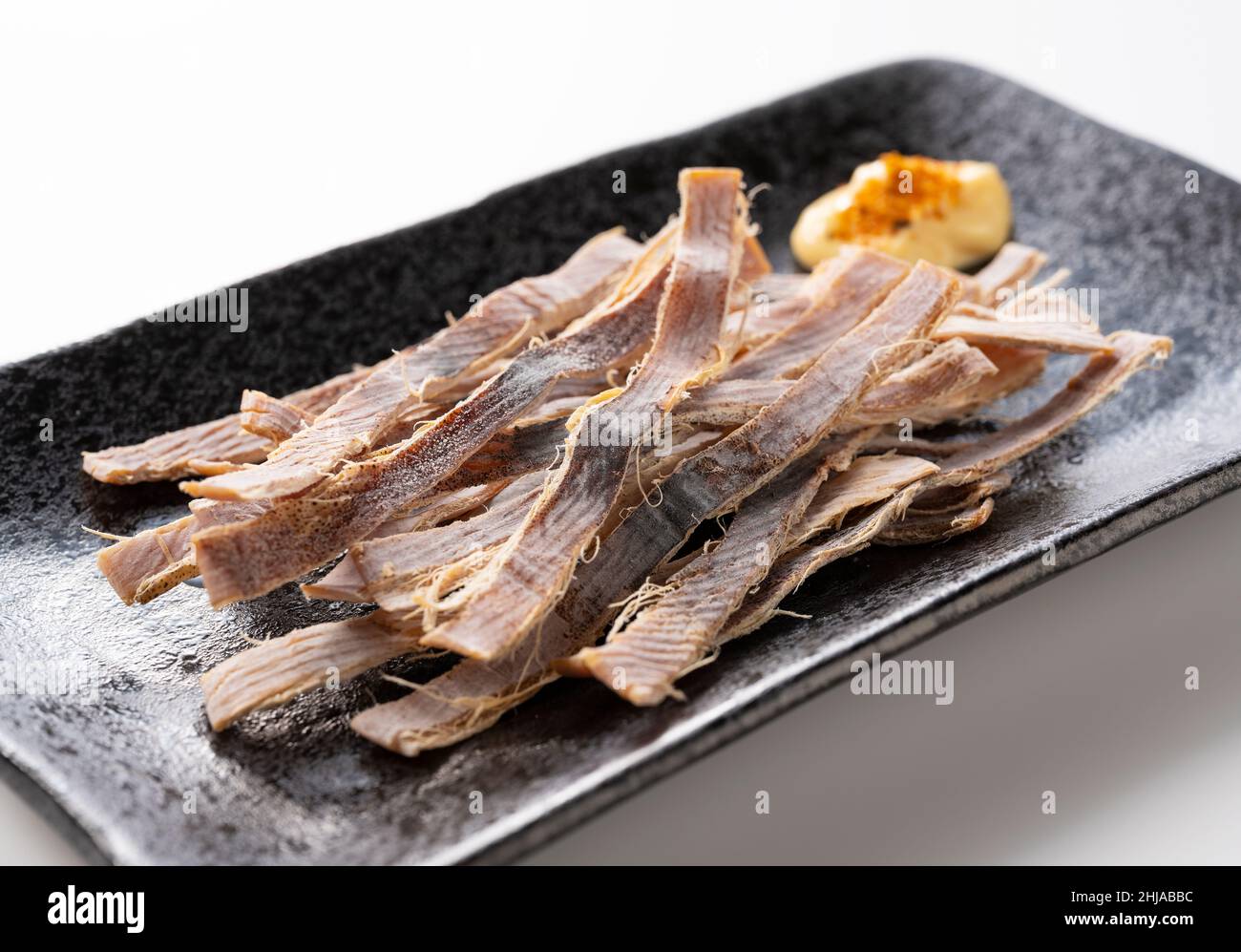 Dried squid and mayonnaise on a plate placed on a white background ...