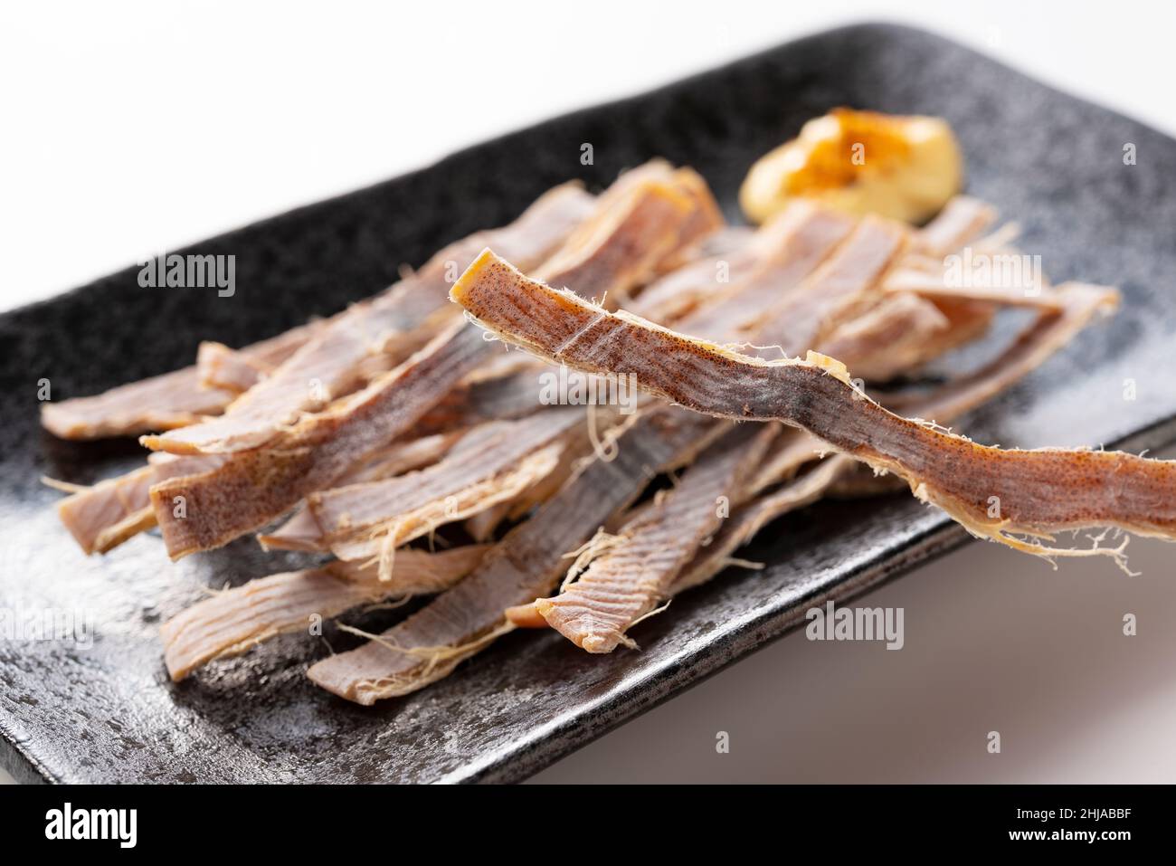 Dried squid and mayonnaise on a plate placed on a white background ...