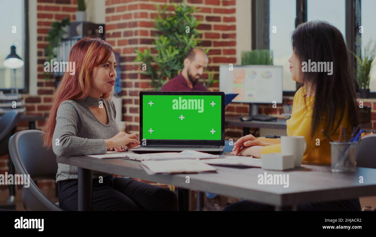 Business people looking at laptop with green screen and working to ...