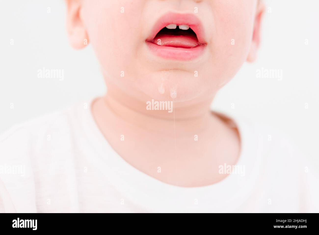 Close-up to babys mouth with two teeth. Drool is drooling from his ...