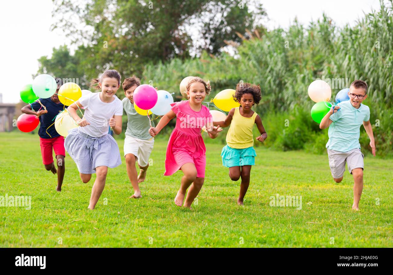 Kids with balloons running through field Stock Photo - Alamy
