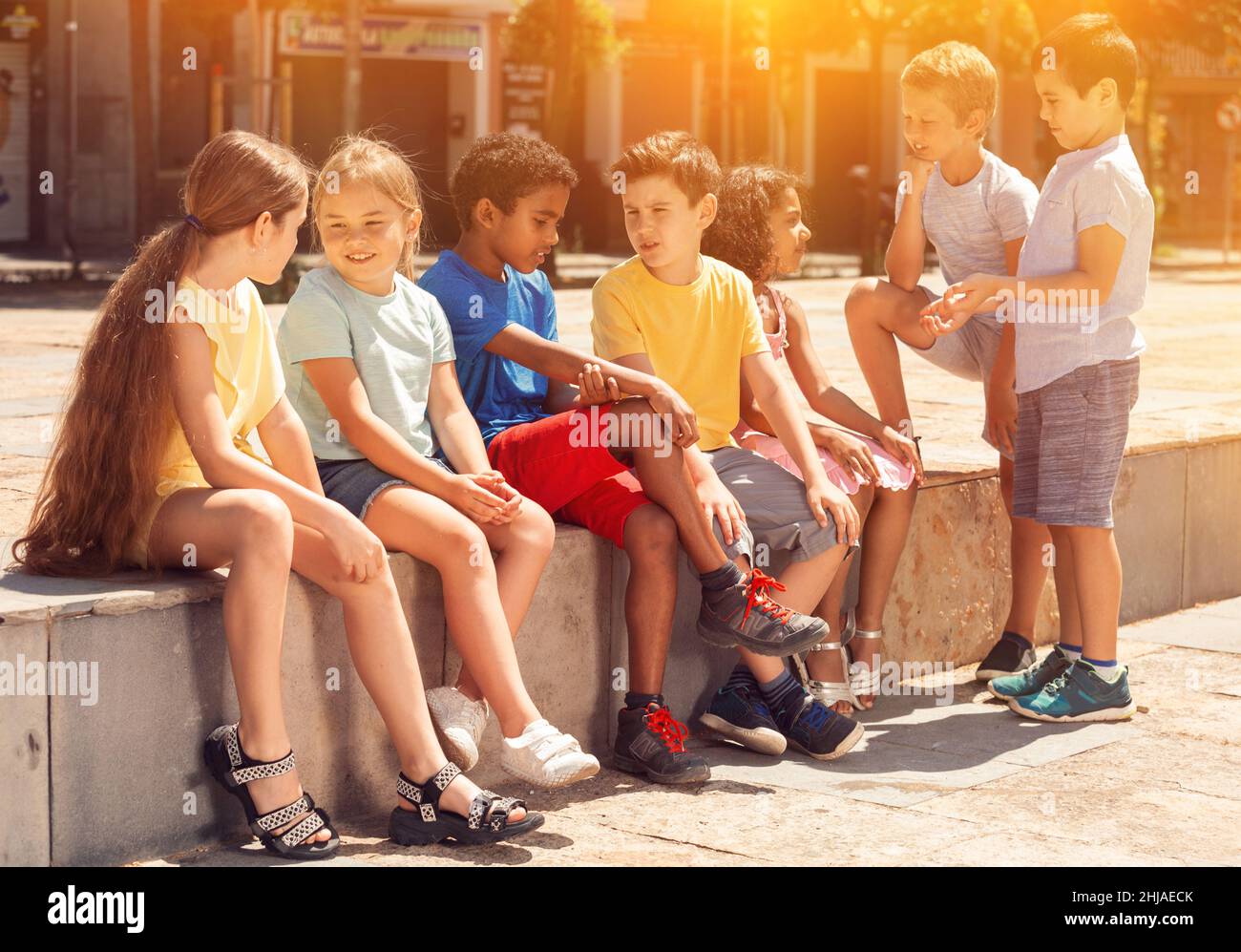 Positive children chatting together sitting at urban street Stock Photo ...