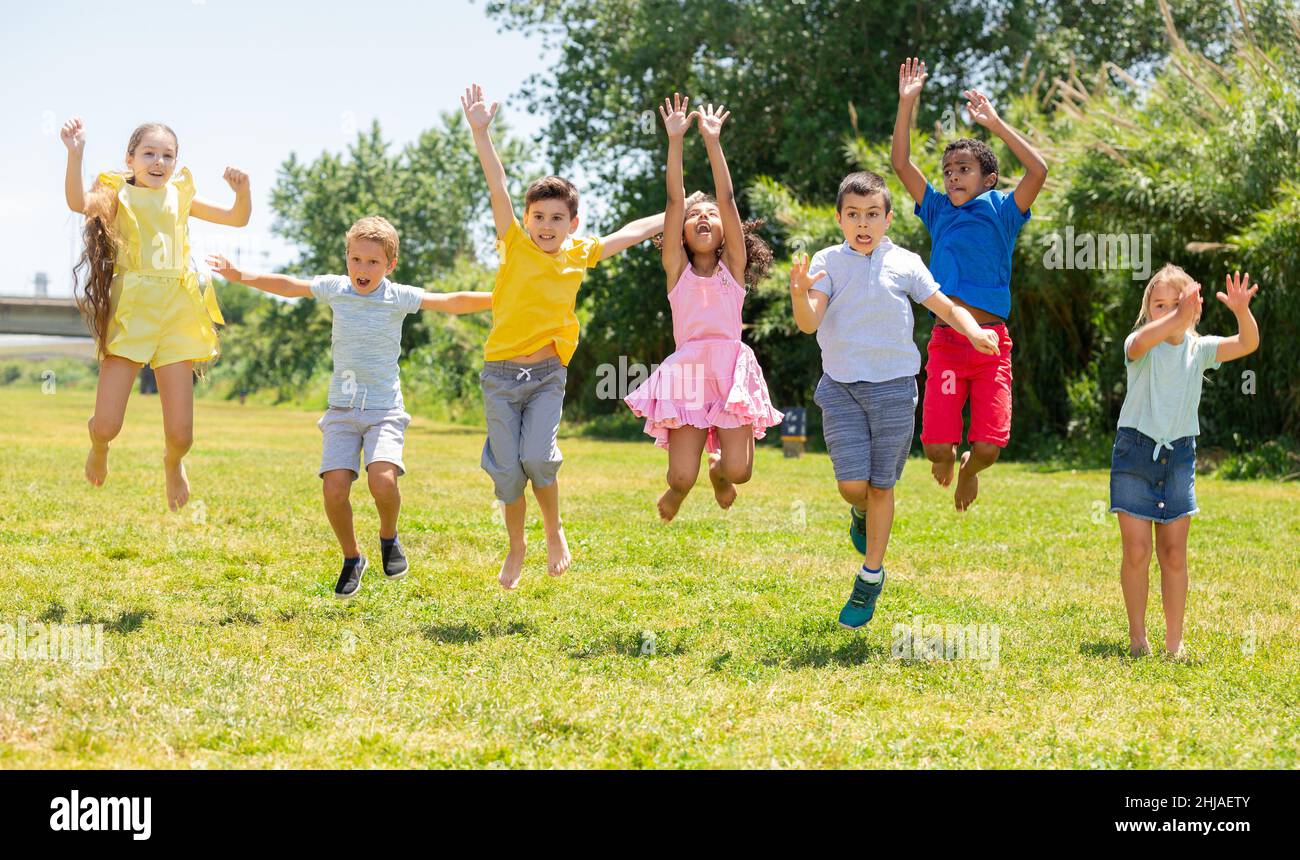 Happy school children jumping on the green lawn in park Stock Photo - Alamy