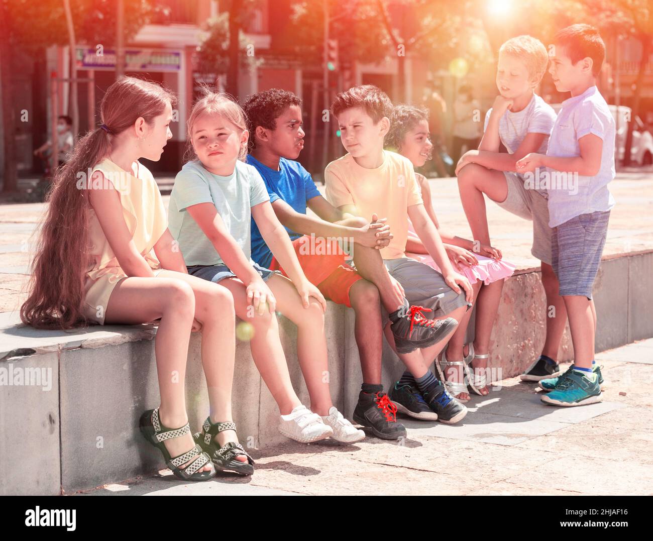 Positive children chatting together sitting at urban street Stock Photo ...