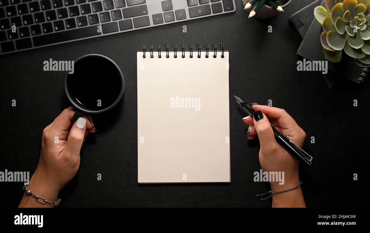 Modern dark workstation with hipster woman hands writing on spiral ...