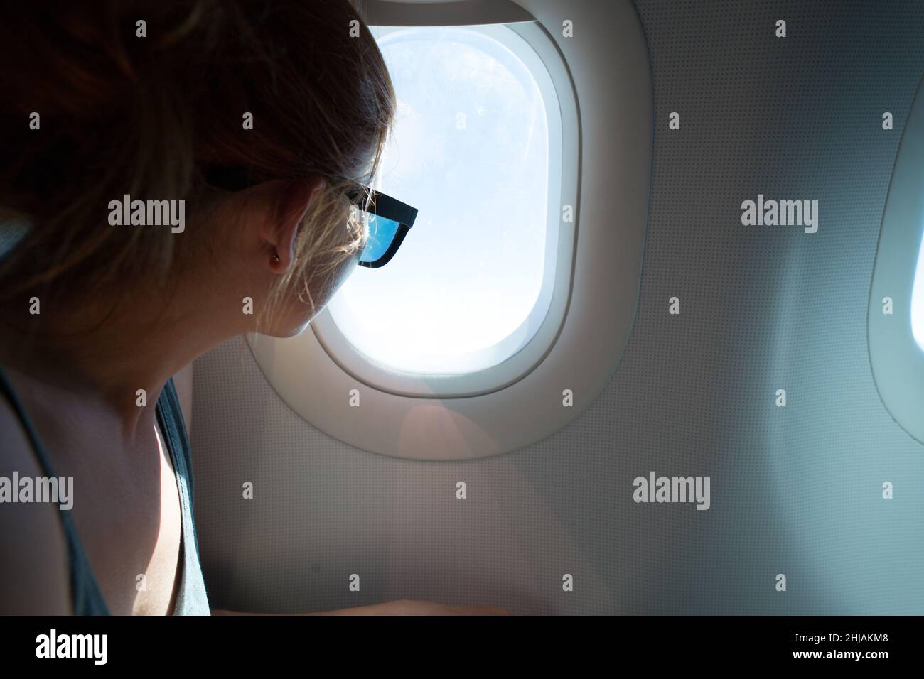 Closeup of a girl looking through the window of a plane Stock Photo - Alamy
