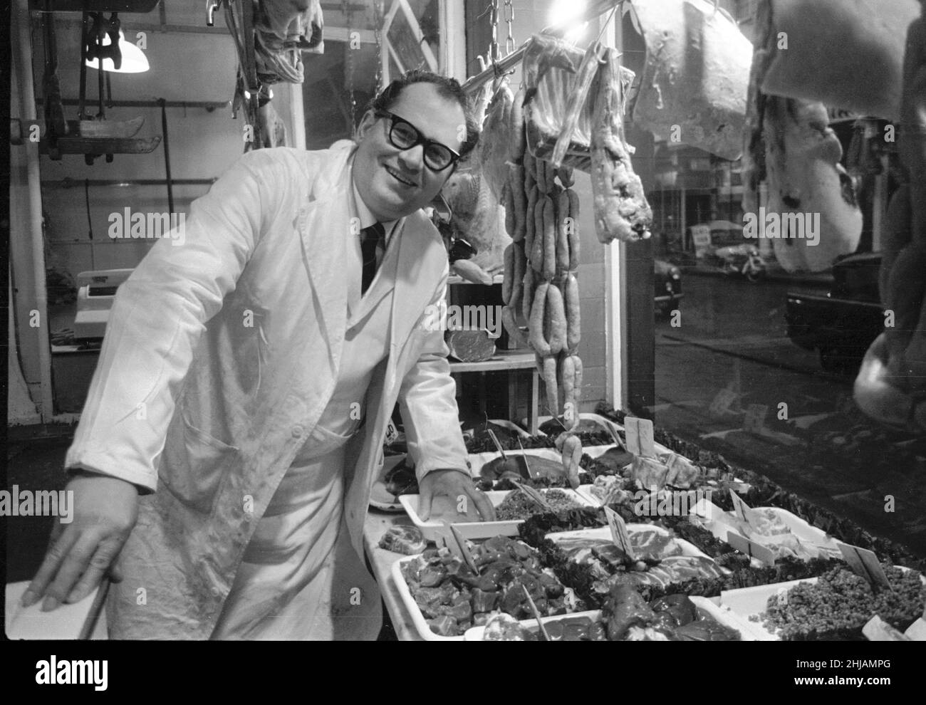 Butcher stands proudly in his shop as his various meat products are ...
