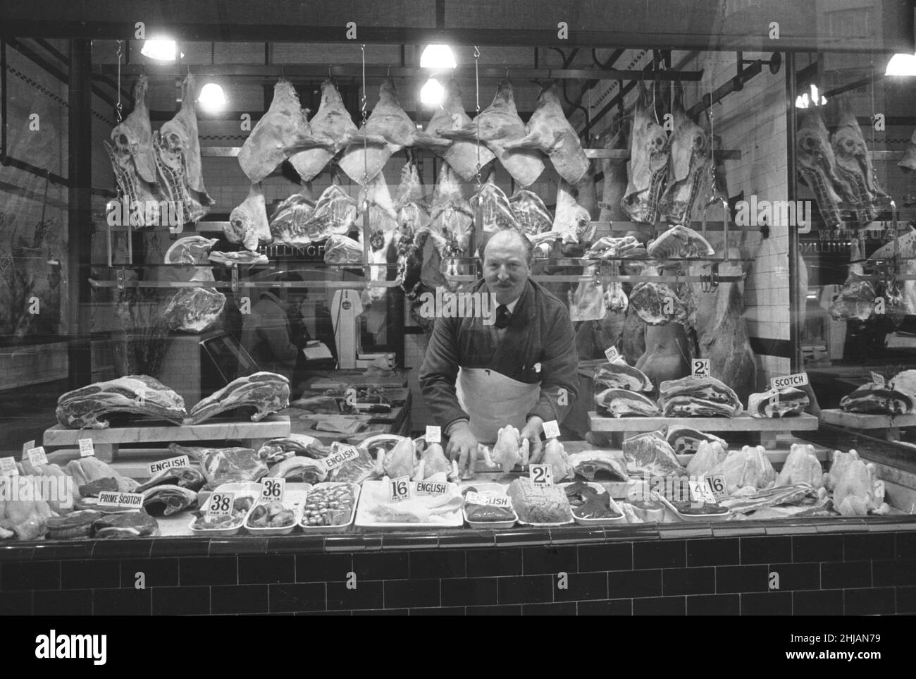 Butcher standing in his shop window, showing off his various meat ...