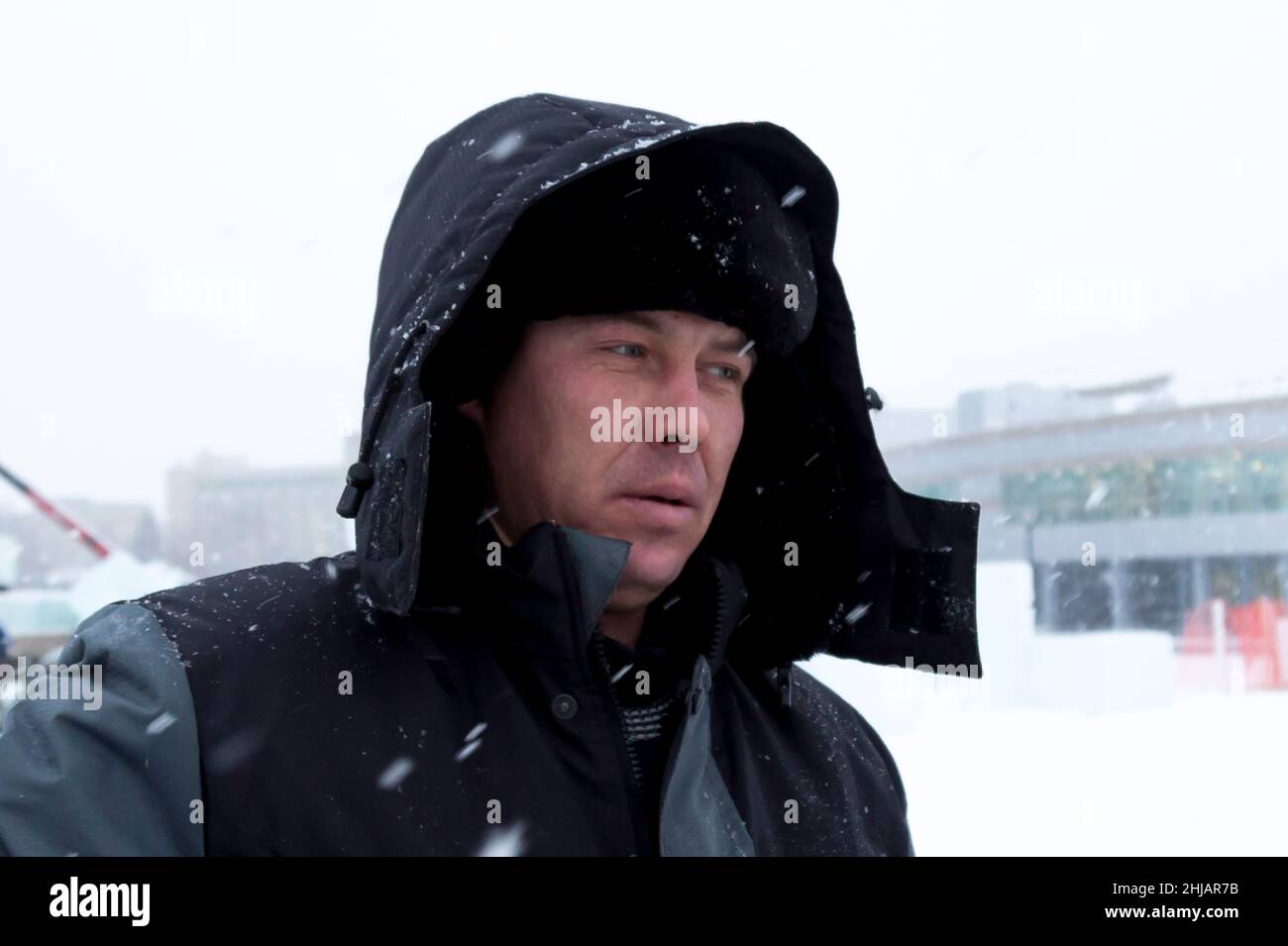 Portrait of a builder at the workplace in a winter suit, with a hood on ...