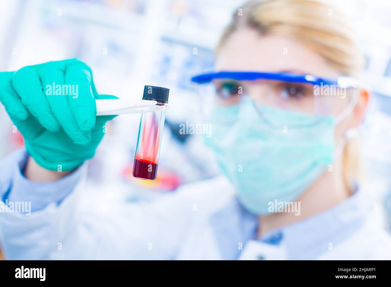 young woman in a medical laboratory with a sample of cell therapy ...