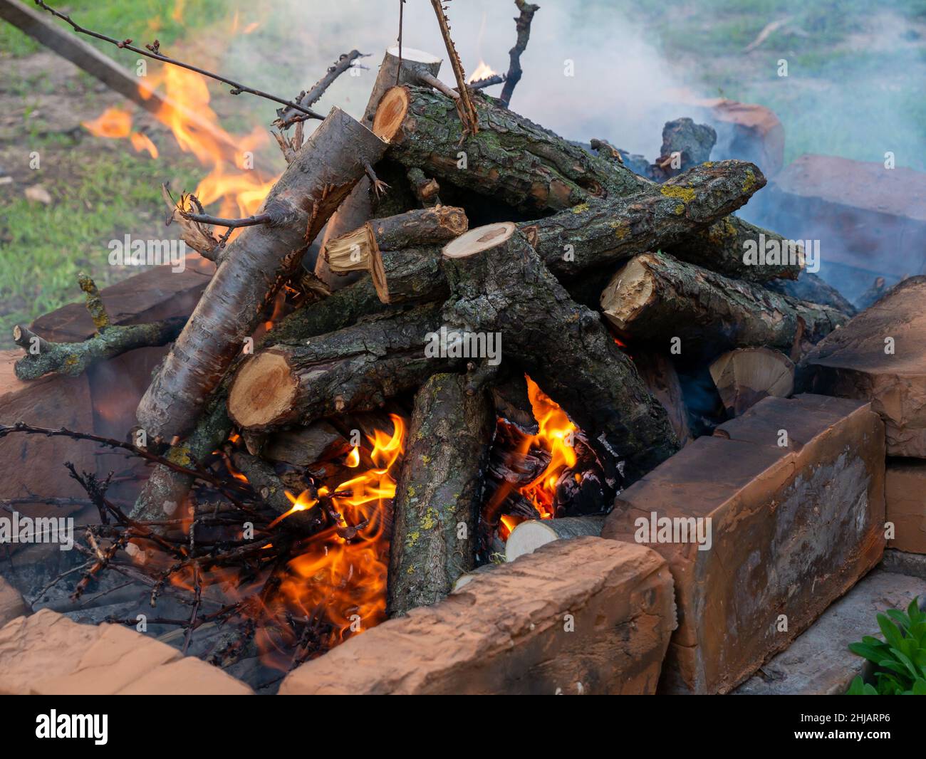 Roaring fire with blurred flames from wood logs in a stone firepit ...