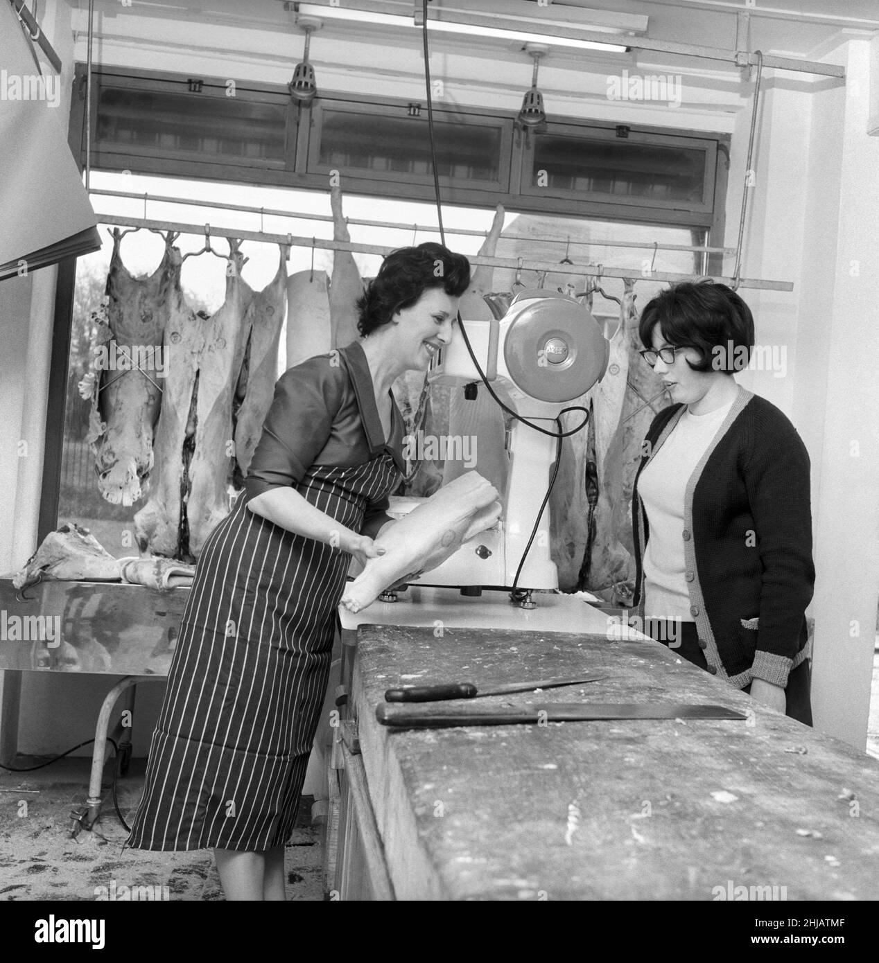 A female butcher seen here at work in her shop, serving a customer at ...