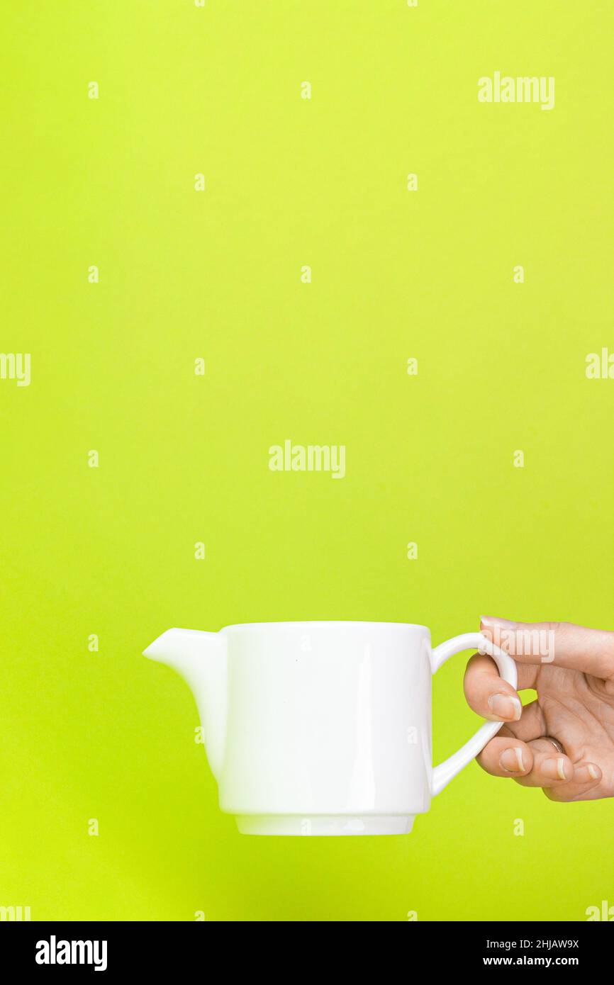Side view of white ceramic teapot in hand. Tea preparation minimal ...