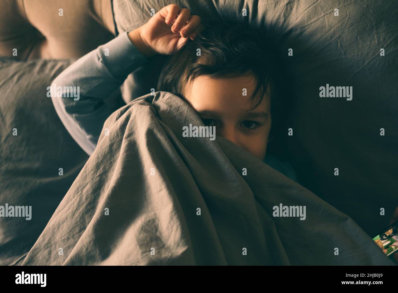 A little boy hides under the covers in bed and smiles Stock Photo - Alamy