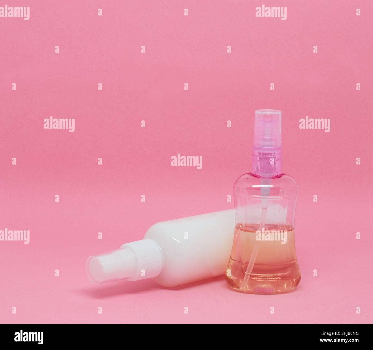 Two spray bottles on a pink background Stock Photo - Alamy