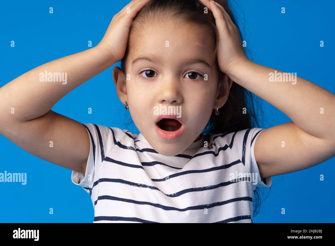Shocked little girl looking with amazement on blue background Stock ...